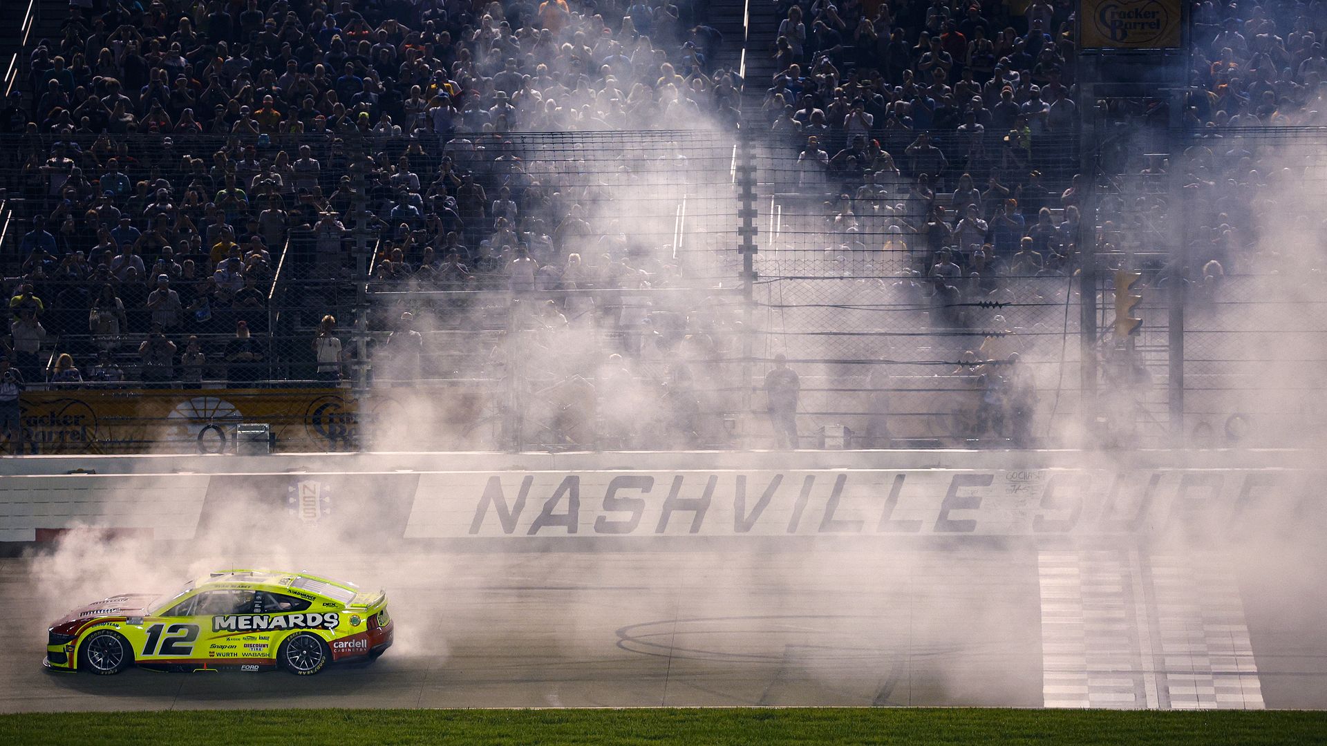 a pic of a nascar car passing the finish line with smoke coming out of ...